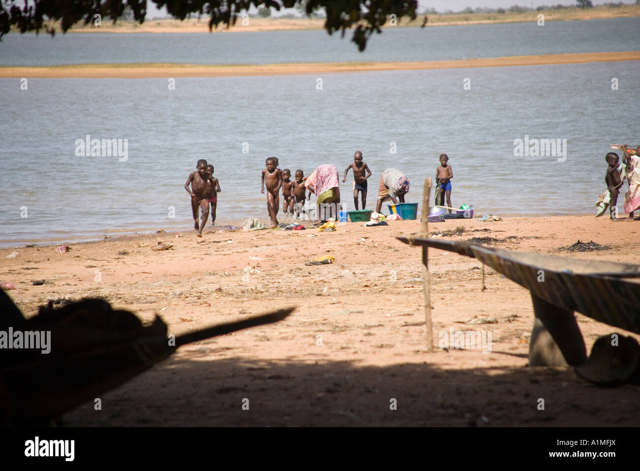 Woman and children washing in the Niger with a baby by the town of ...