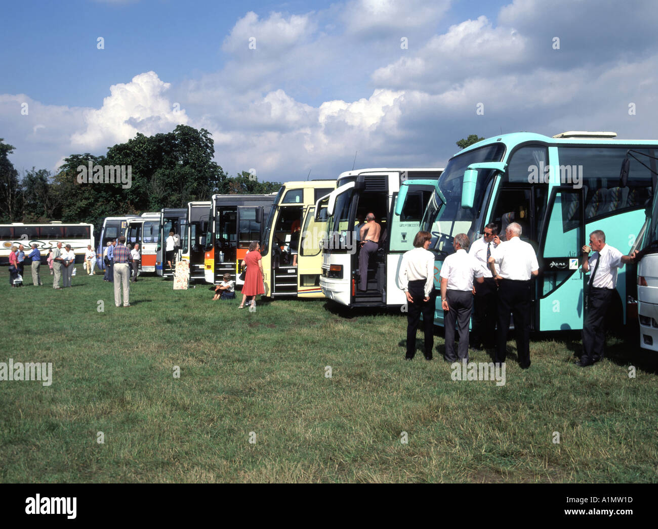 Group of coach bus drivers & rows of coaches parked on grass wait to ...