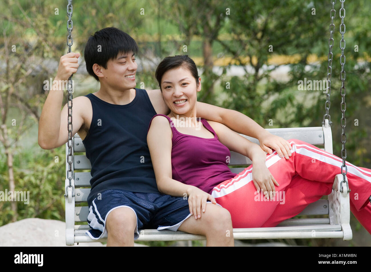 Young couple sitting on a swing together Stock Photo - Alamy