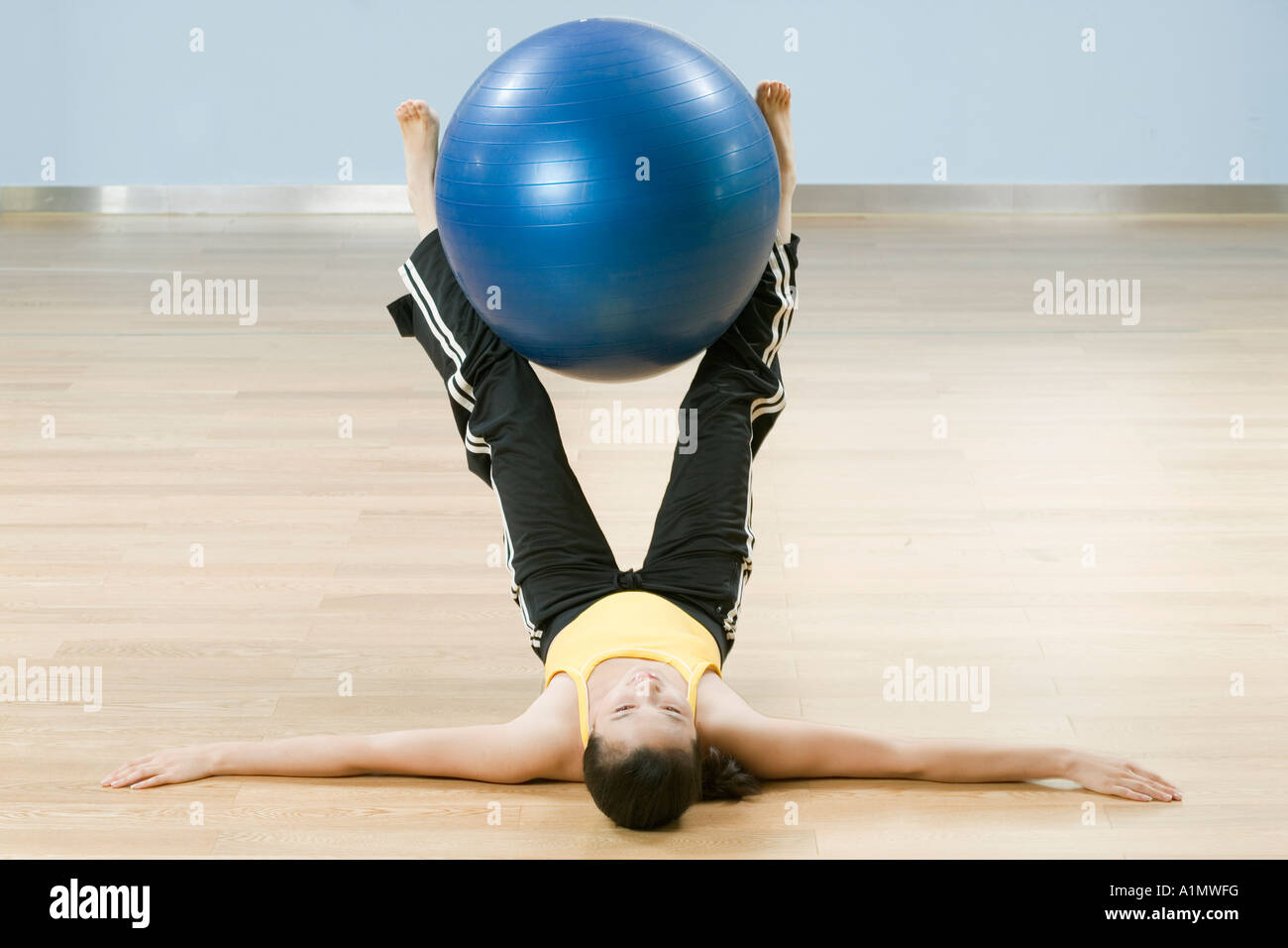 Young woman holding an exercise ball between her ankles Stock Photo - Alamy