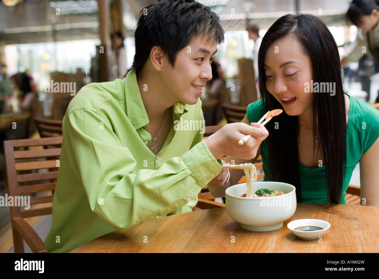 Young couple sharing noodles Stock Photo - Alamy