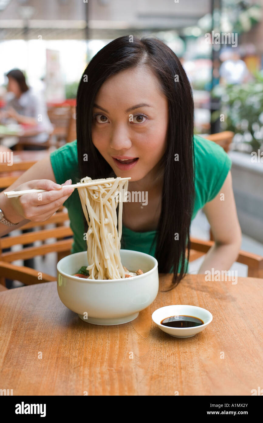Young woman eating noodles Stock Photo - Alamy