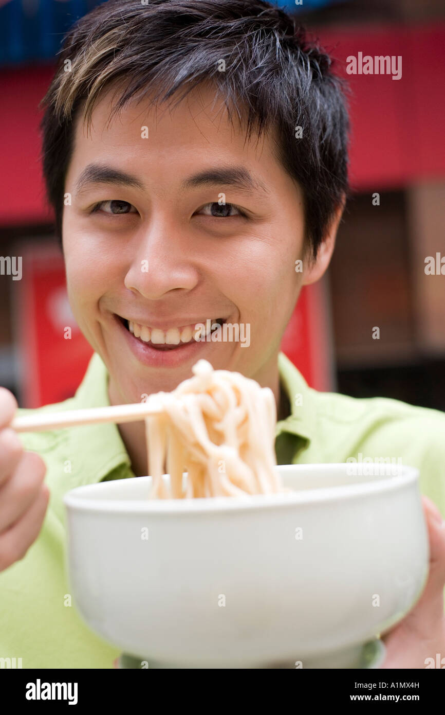 Young man eating noodles Stock Photo - Alamy