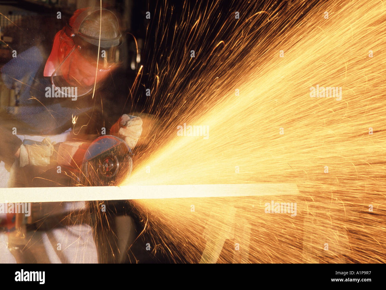 Workman in protective safety gear using a hand held disc cutting ...