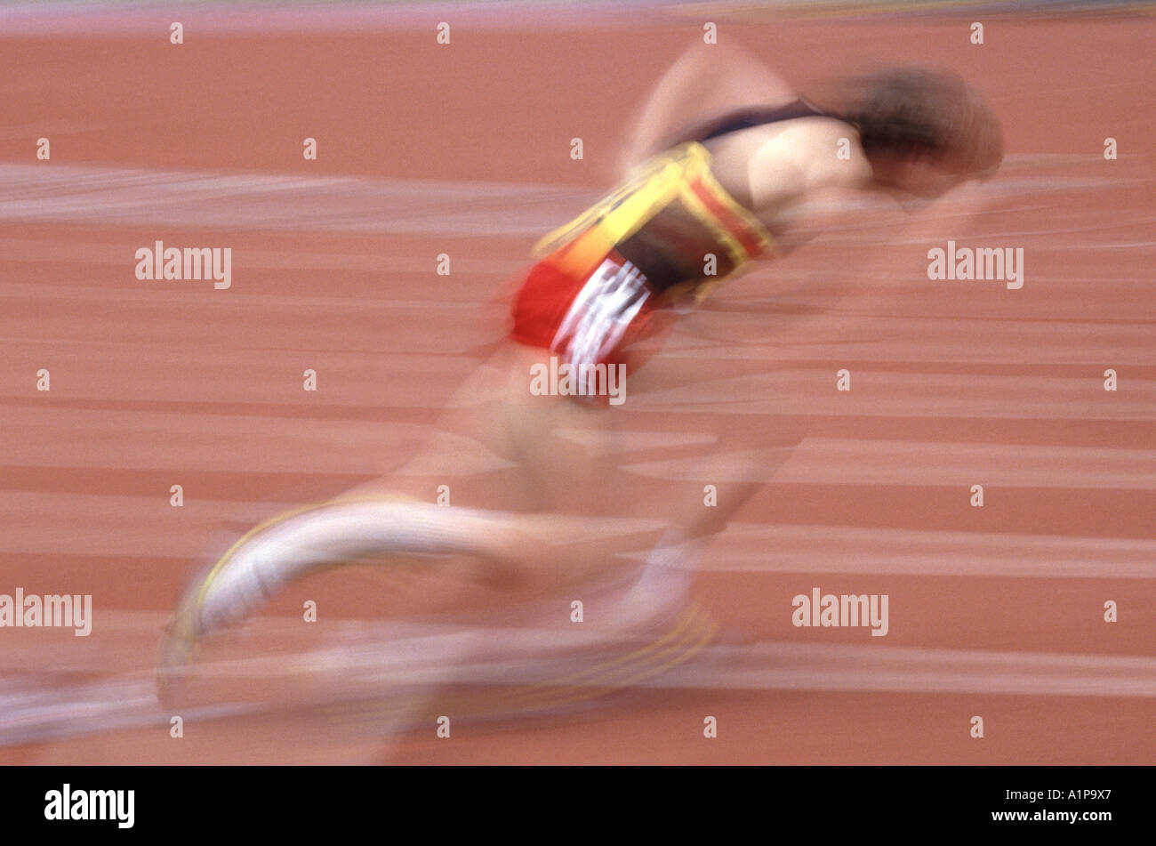 Motion blur image of male athlete leaning forward as he leaves the ...