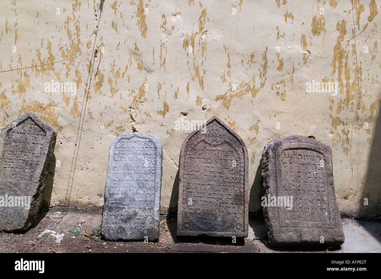 Old headstones with Hebrew inscription rest against the outside wall of ...