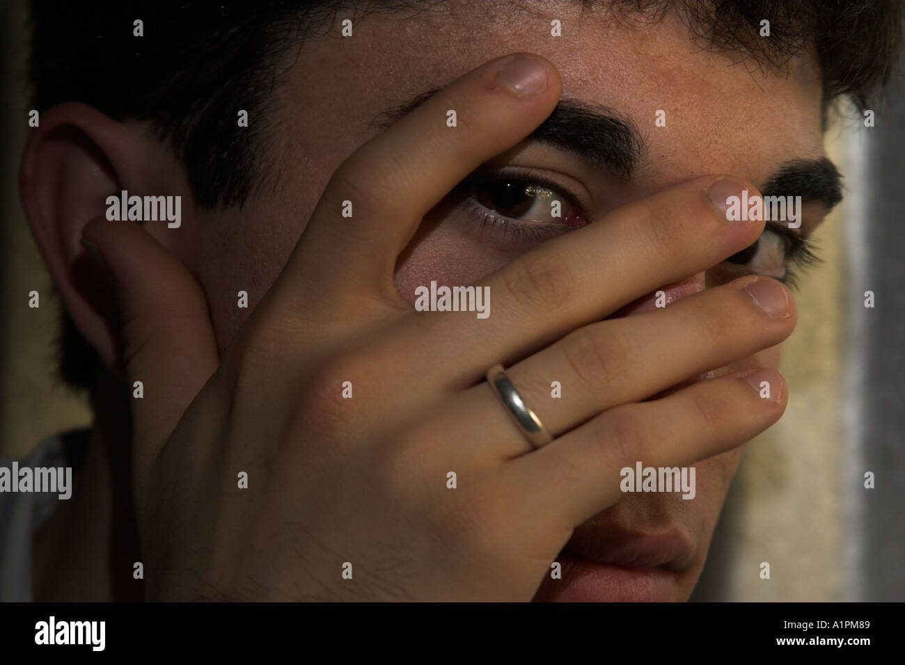 Young man hiding his face behind his hand Stock Photo - Alamy