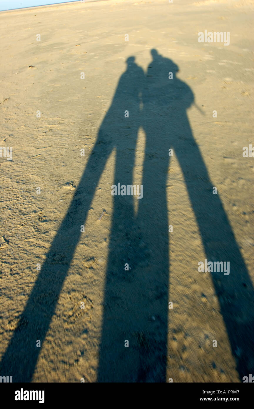Distorted shadows on a beach of a man and woman holding hands Stock ...