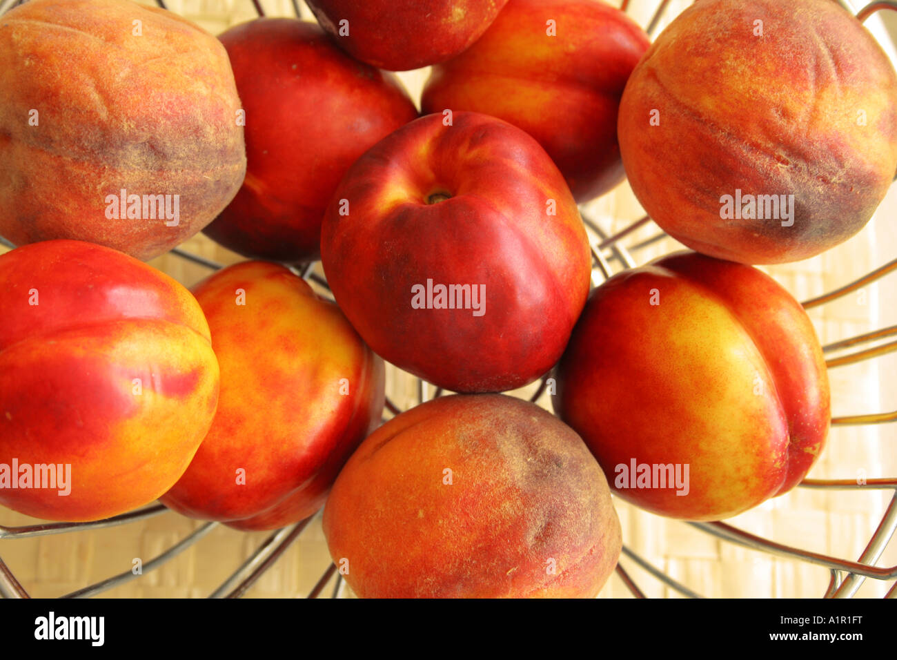 A close-up of ripe, juicy nectarines and peaches in a wire fruit basket ...