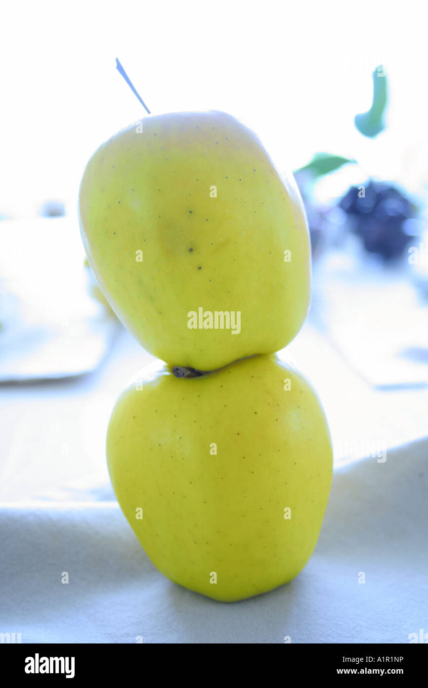 Two yellow apples stacked vertically, with a soft-focus background ...