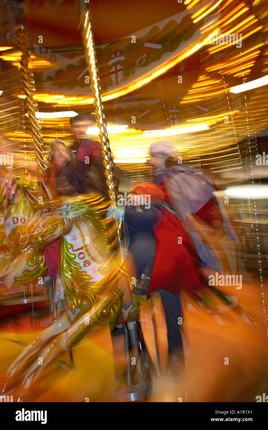 Family on Carousel or Merry go Round in fairground at night with ...
