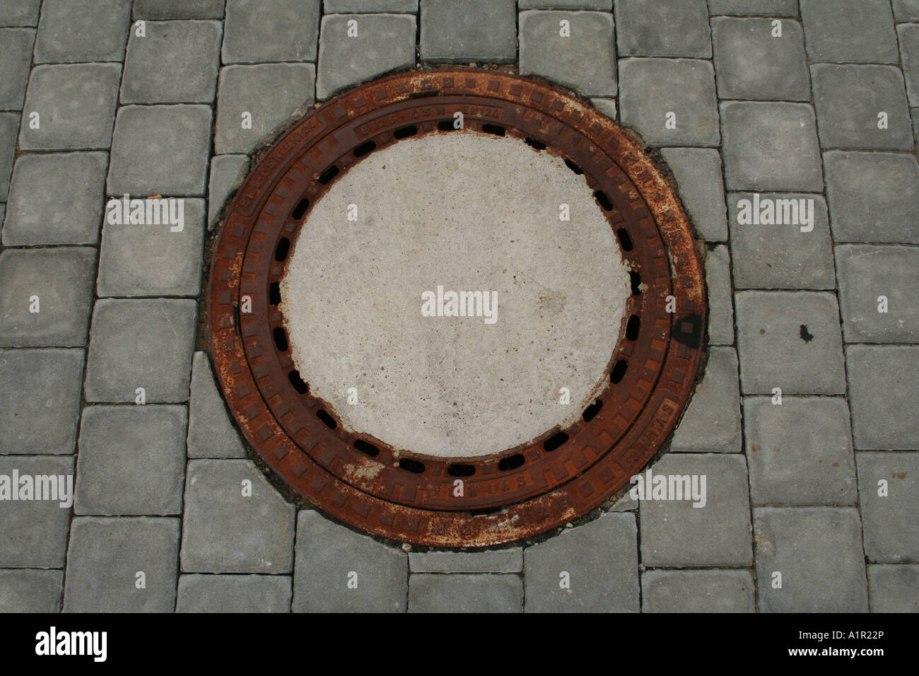 Rusty manhole cover on a stone pavement, showcasing urban ...