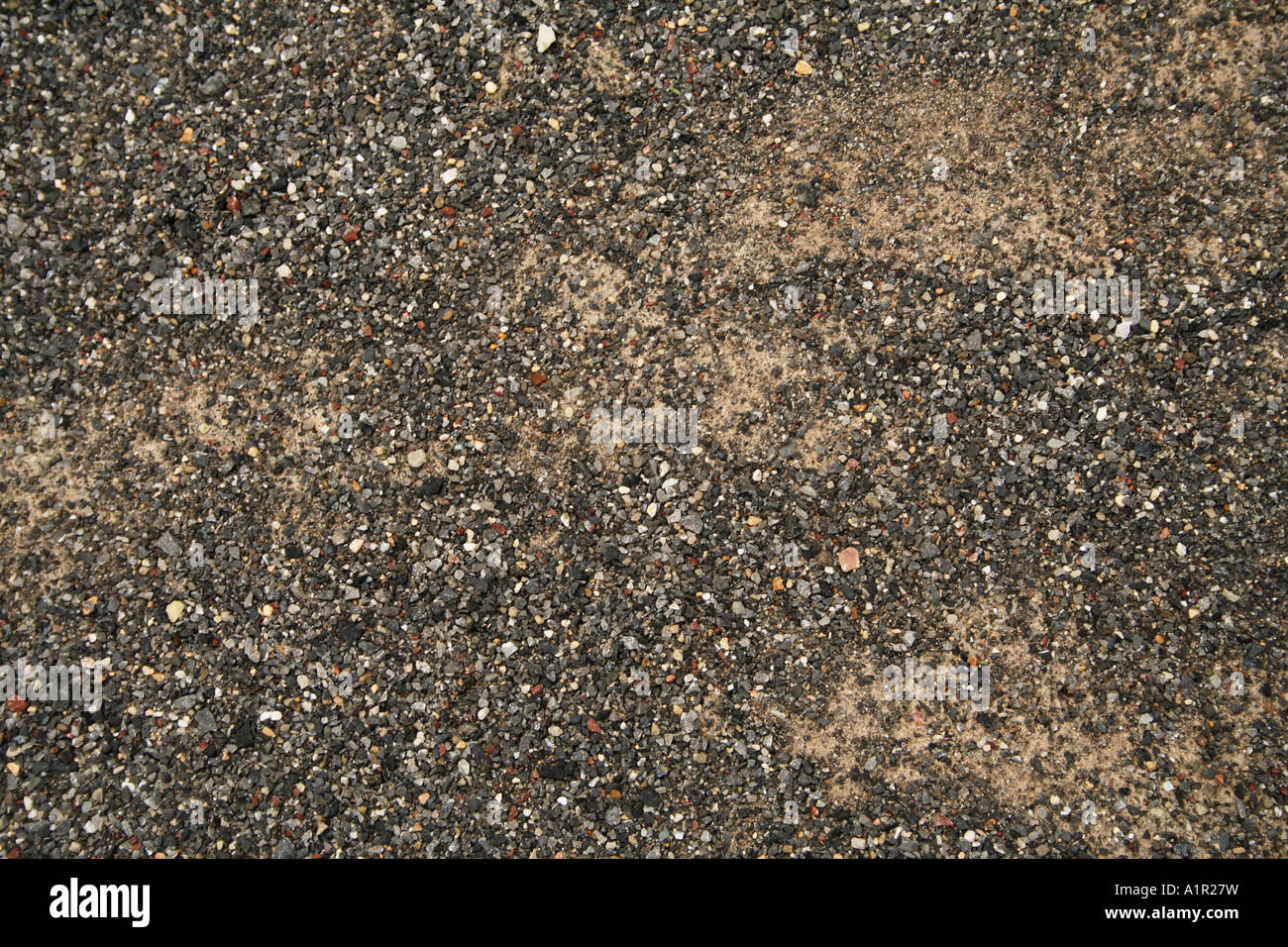 Close-up of asphalt texture with gravel and sand patches, showcasing a ...
