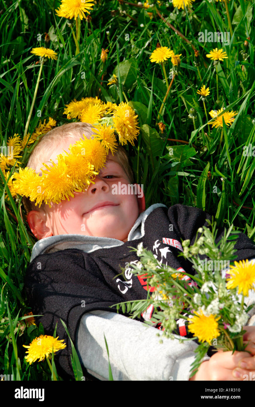 little boy with a bunch of flowers and a garland of dandelion flowers ...