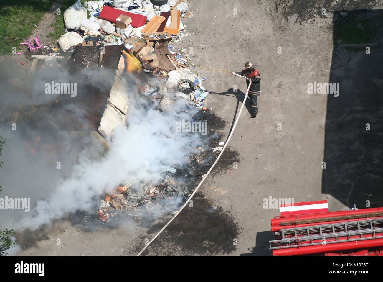 Firefighter extinguishing a burning pile of debris with a hose, Kyiv ...