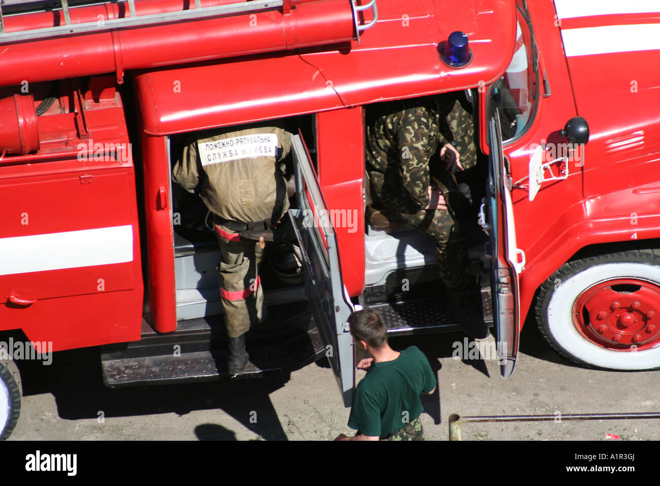 Firefighters in green and protective gear preparing for action beside a ...