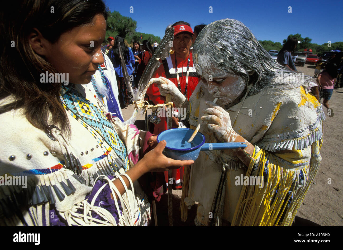 An Apache girl uses a straw to drink water from a dipper during her ...