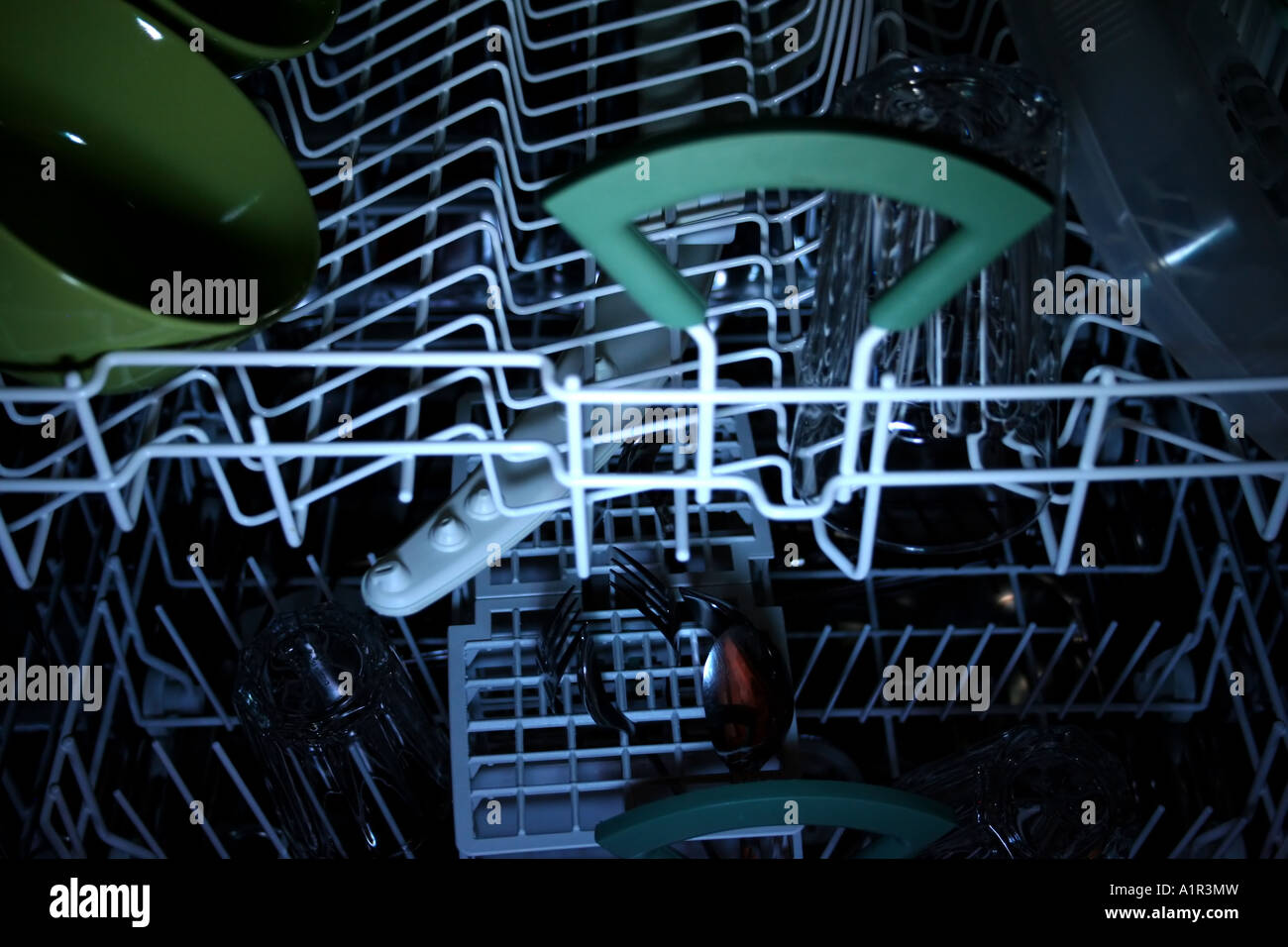 Interior of an empty dishwasher with green dishes placed on the racks ...