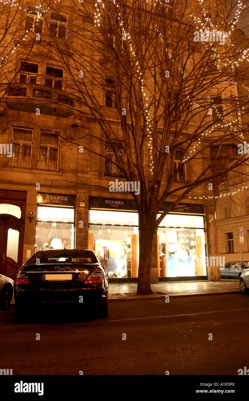 Illuminated street at night with Hermes storefront and luxury cars ...