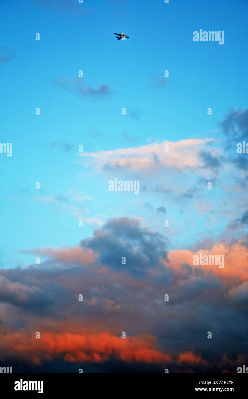 Airplane flying across a vibrant blue sky with scattered clouds at ...