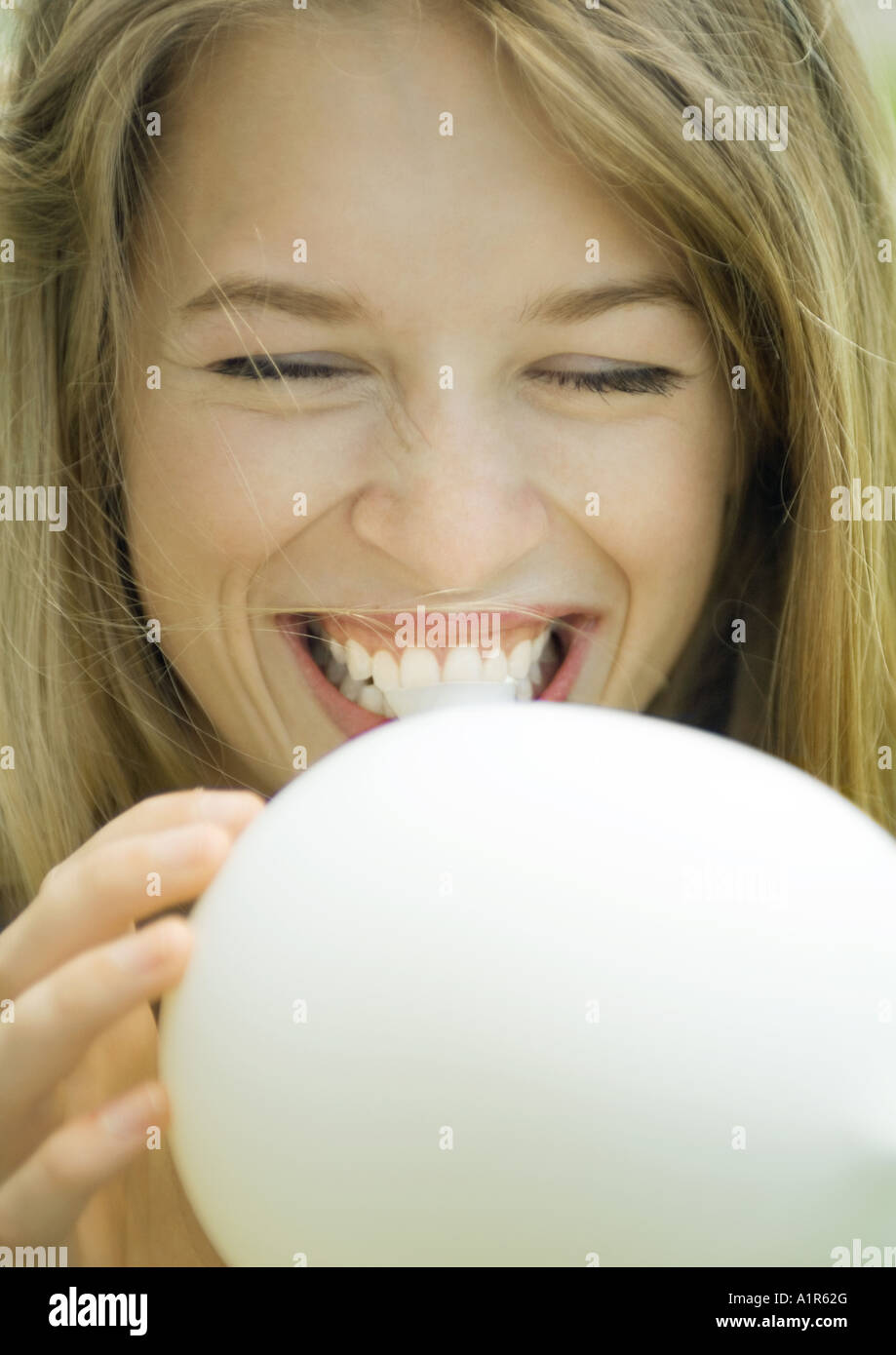 Young woman blowing up balloon, laughing, close-up Stock Photo - Alamy