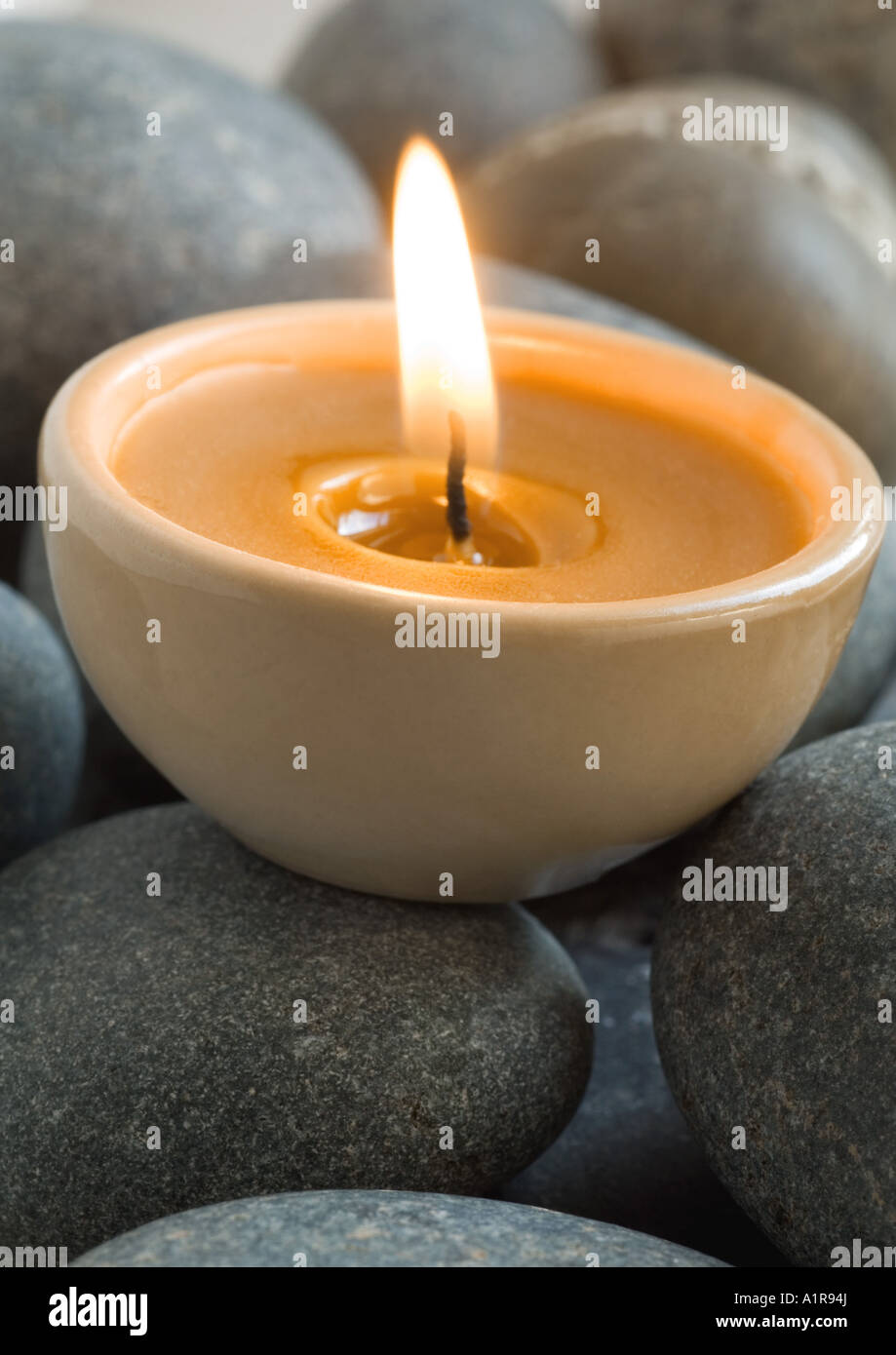 Lit candle on stones Stock Photo - Alamy