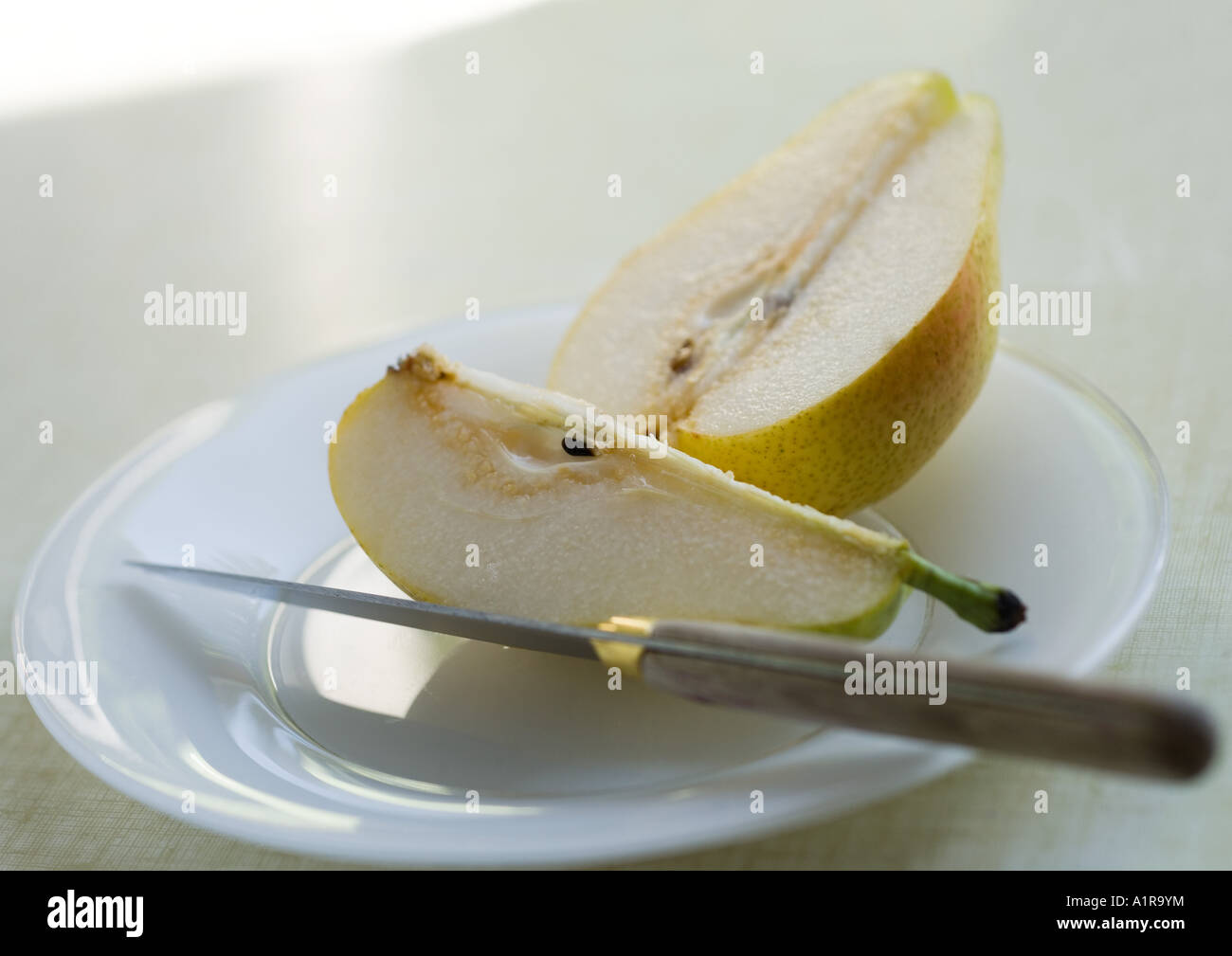 Pear, cut on dish, with knife Stock Photo - Alamy