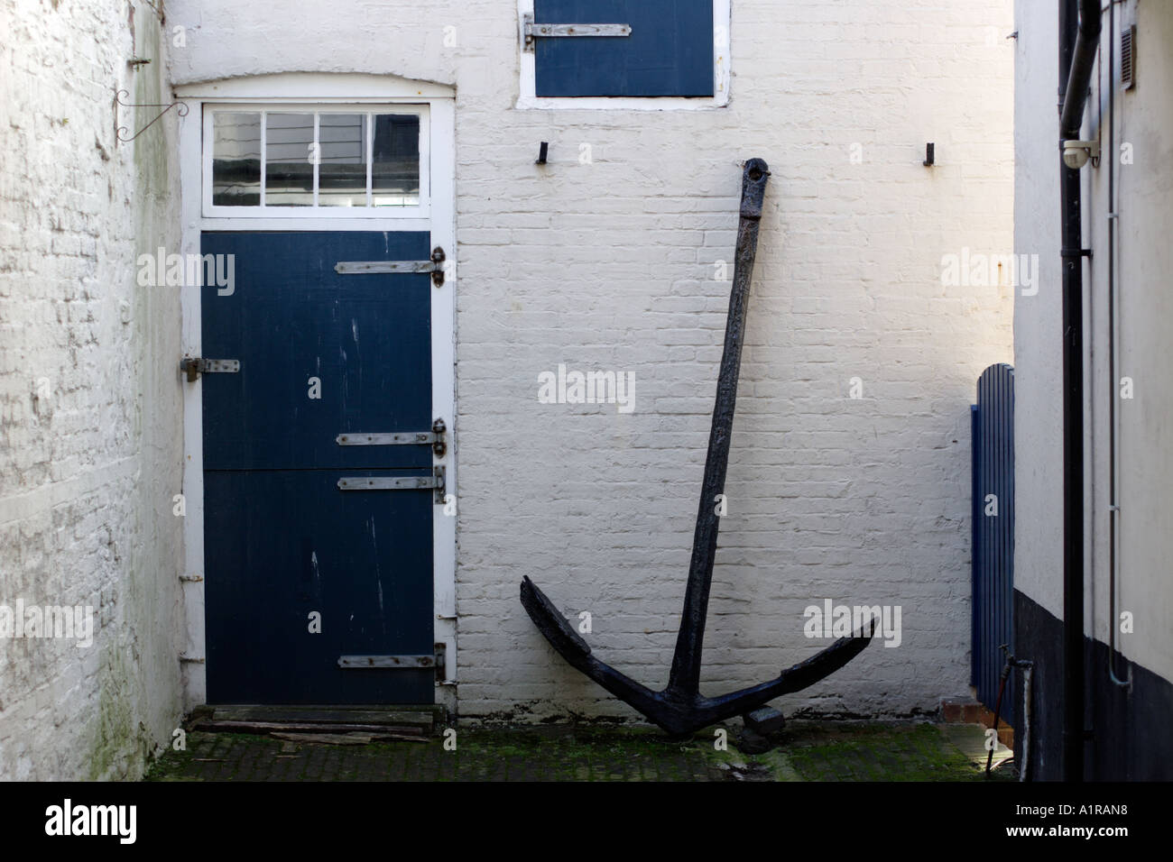 Rusty iron ships anchor leaning against white painted wall in Victorian ...