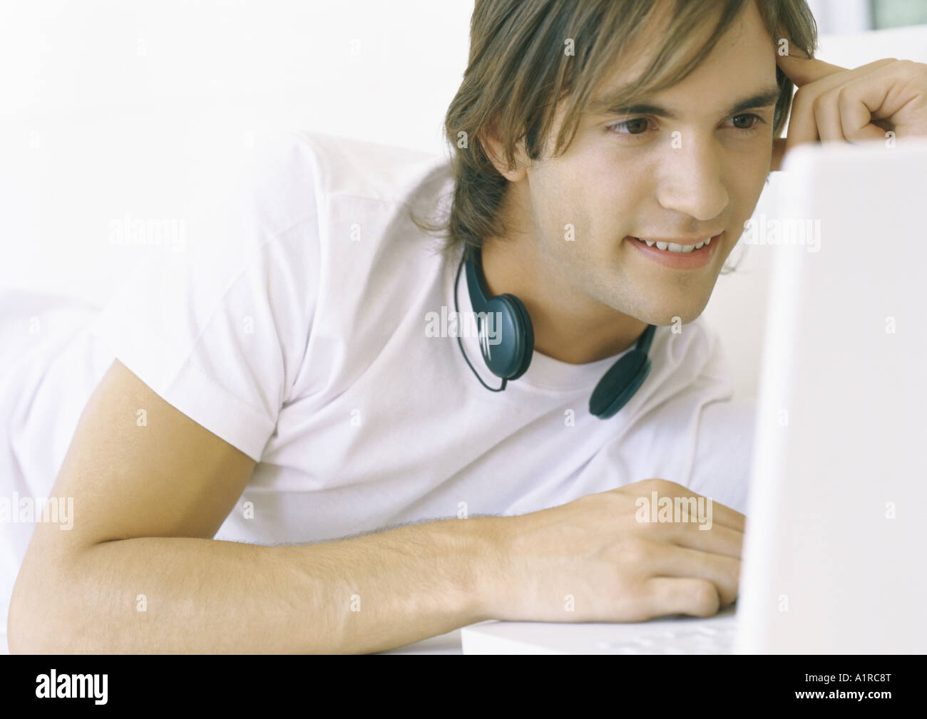 Man using laptop, headphones around neck Stock Photo - Alamy
