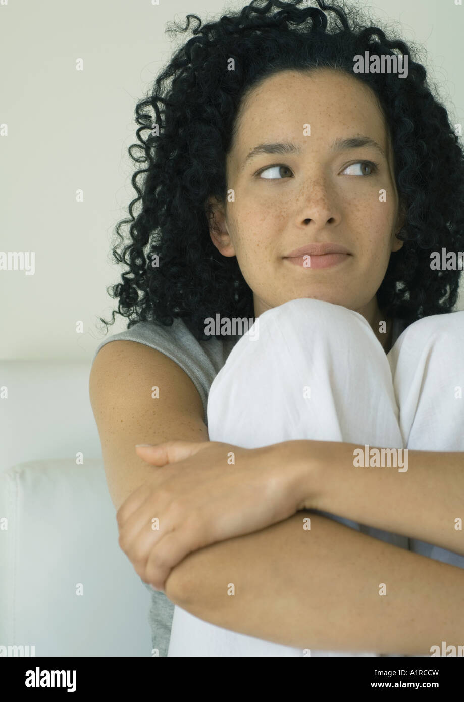 Young woman hugging knees Stock Photo - Alamy