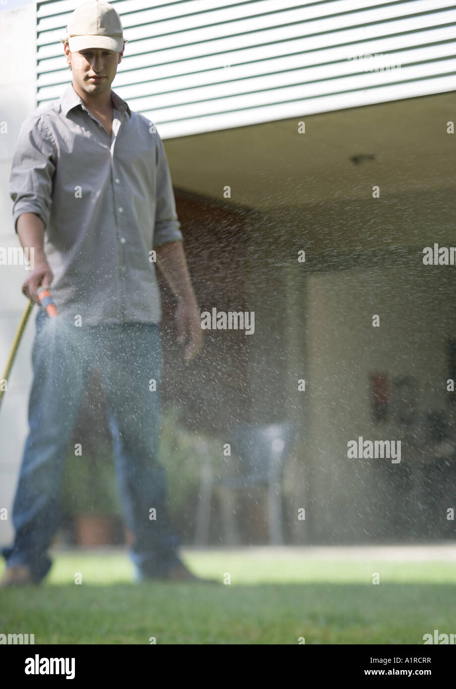 Man doing yardwork, using garden hose Stock Photo - Alamy