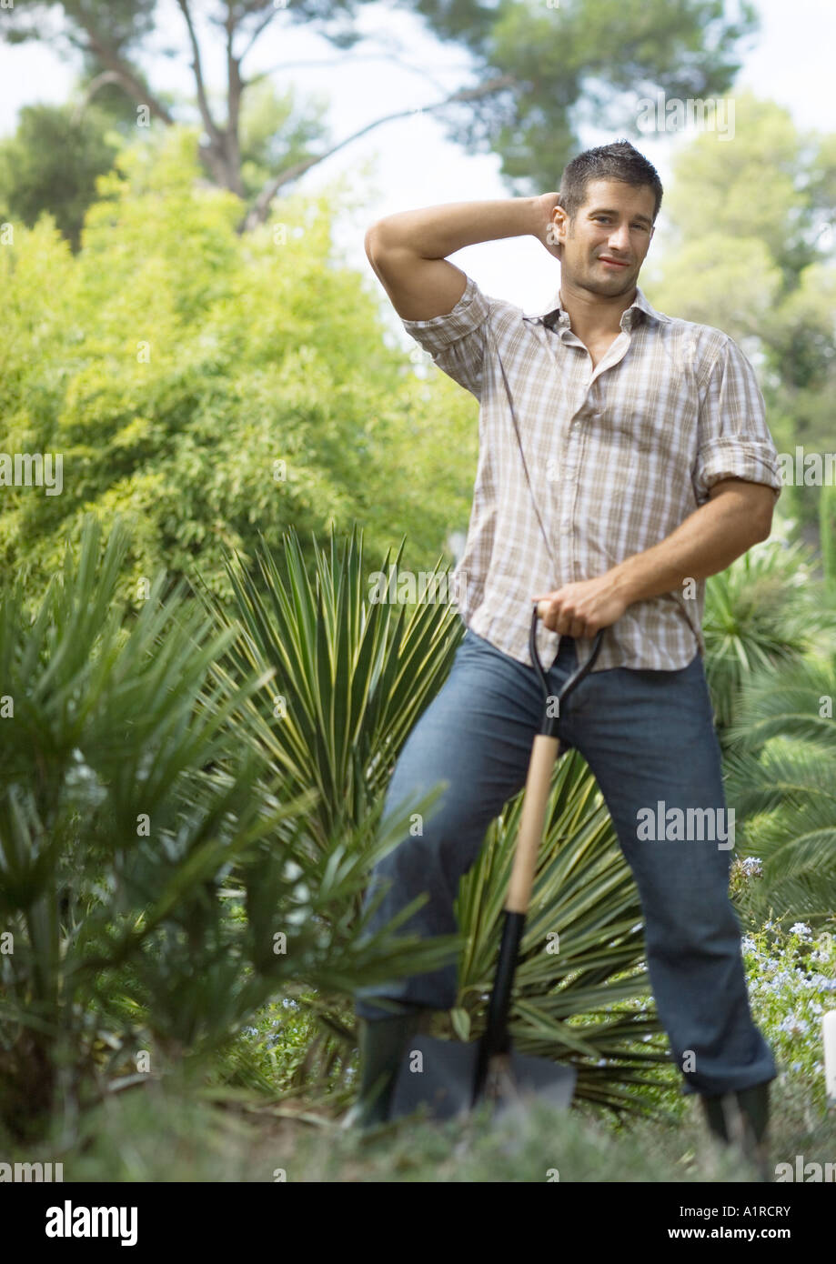 Man doing yardwork, standing with hand behind head Stock Photo - Alamy