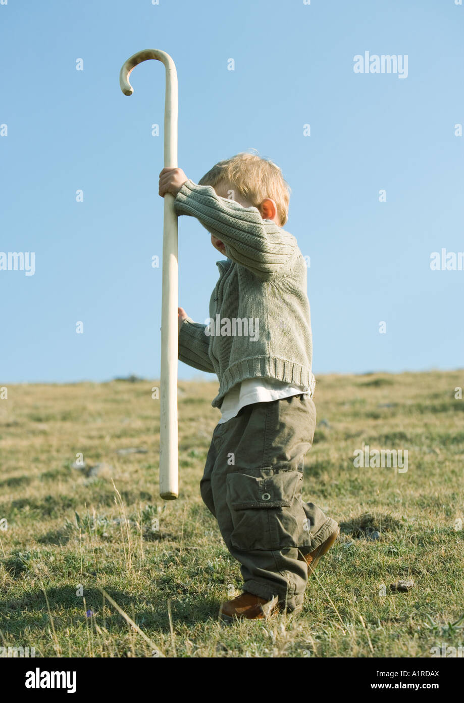 Boy holding cane on hill Stock Photo - Alamy