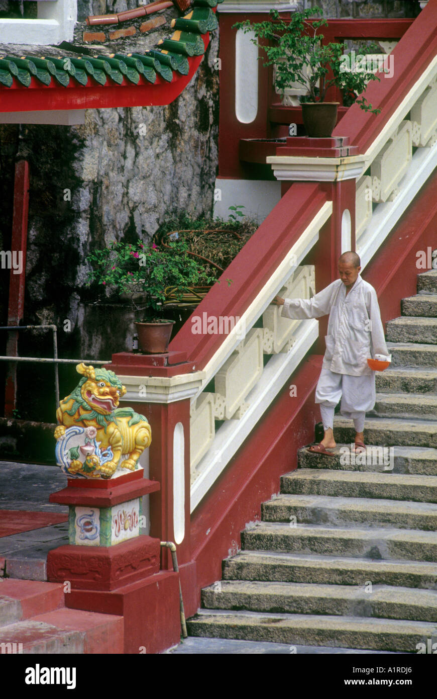 A buddhist goes down the steps of a temple in Penang, Malaysia Stock ...
