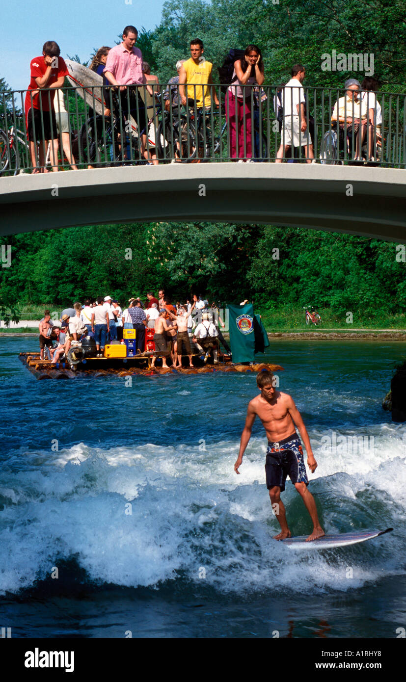 One surfer and people doing a voyage by raft on river Isar at Munich ...