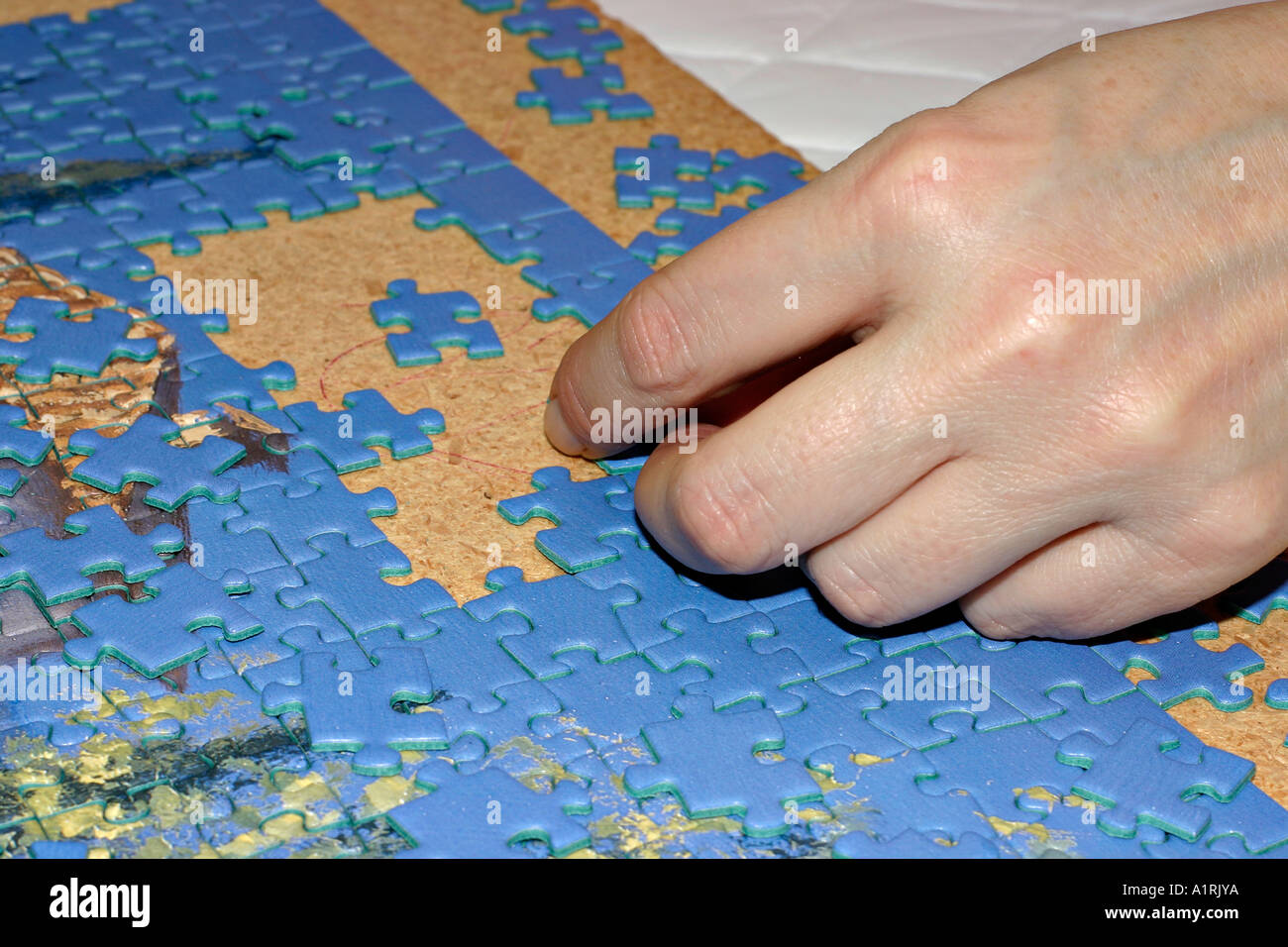 A woman s hand places pieces in a mostly blue section of a complex ...