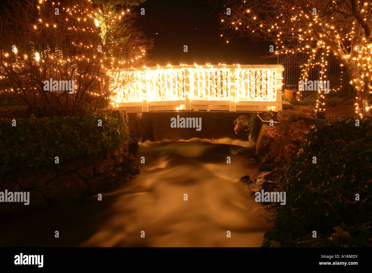 A white bridge over a stream lit with christmas lights at nigth Stock ...
