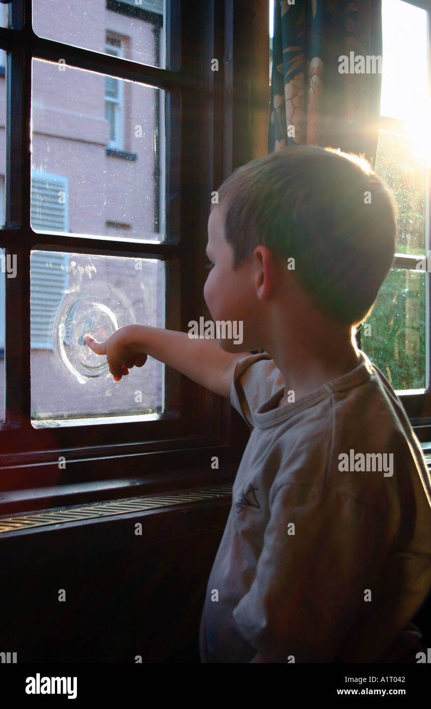 A curious young boy pointing with finger pressed against centre of a ...