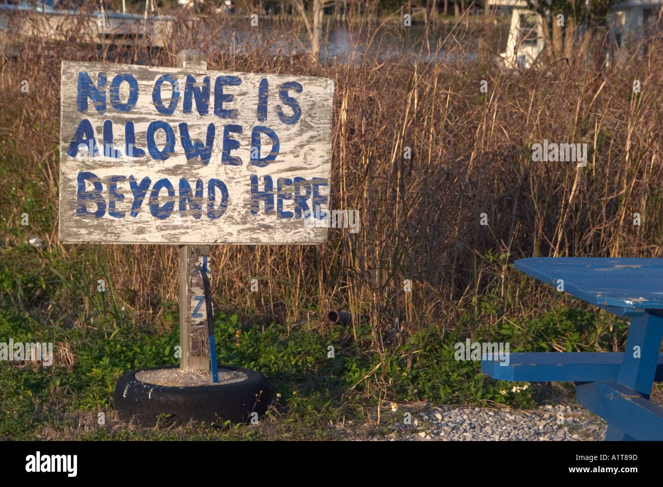 A faded hand painted sign with blue lettering saying No one is allowed ...