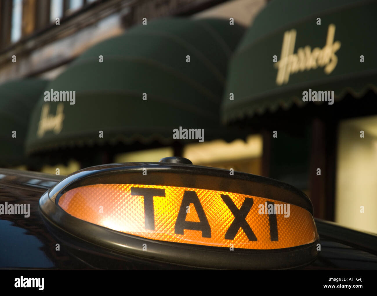 Black taxi cab sign illuminated waiting outside Harrods London England ...