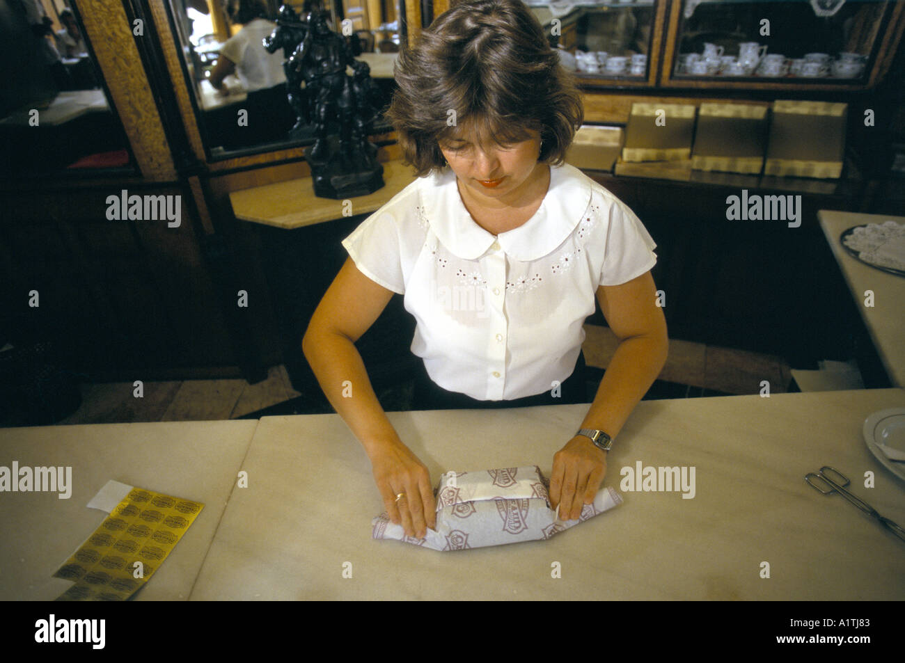 WOMAN STANDING BEHIND COUNTER WRAPPING CAKE IN PAPER AT THE GERBEAUD ...
