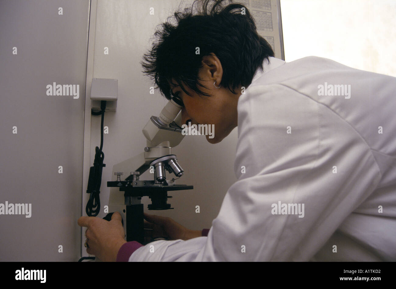 MOBILE GYNAEC CLINIC DEC 1994. Doctor checks sample through microscope ...
