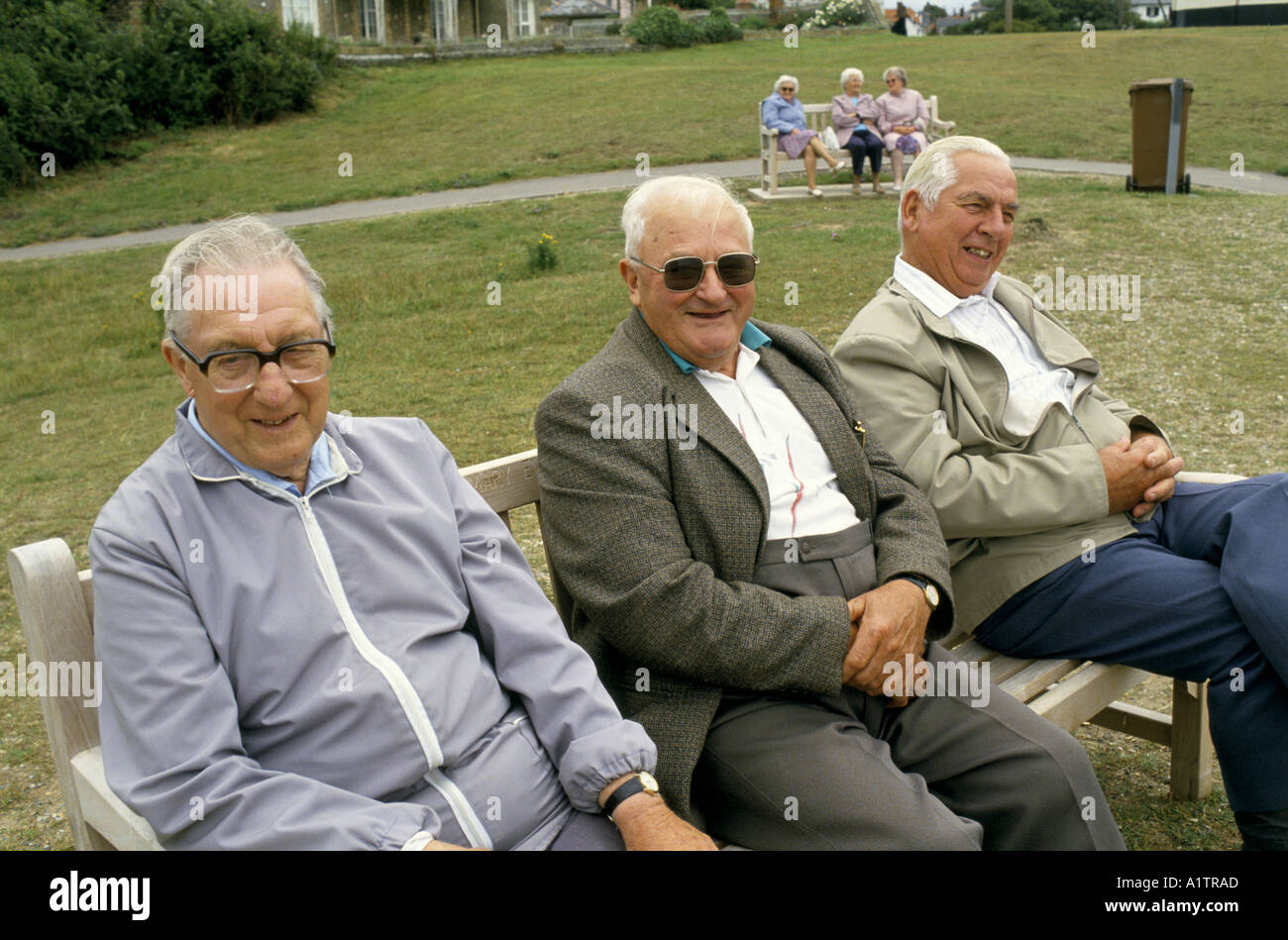3 ELDERLY MEN SITTING ON BENCH IN PARK ON A DAY TRIP IN BACKGROUND 3 ...