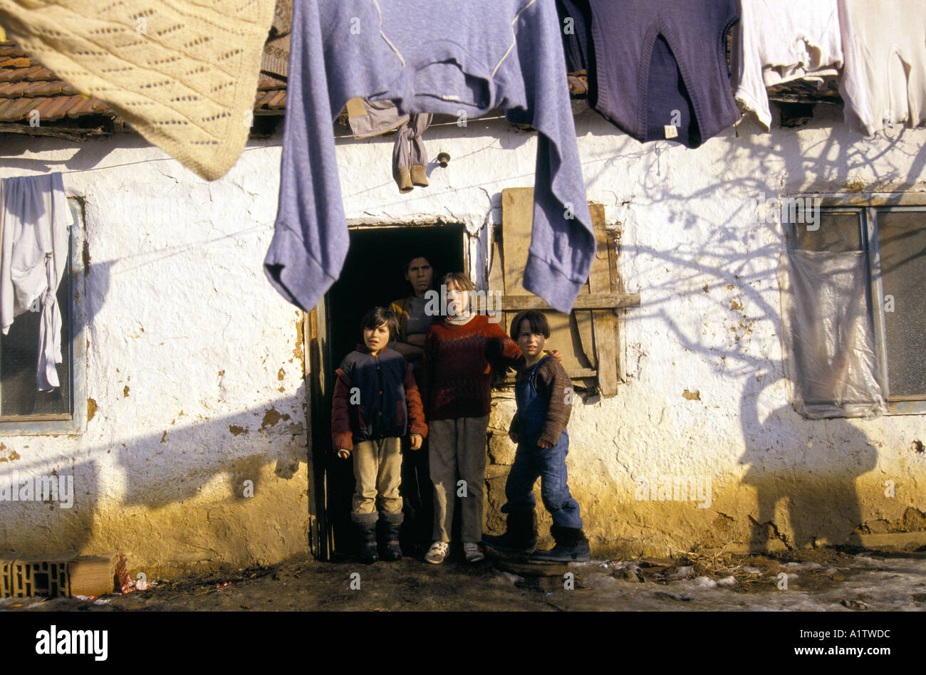 POOR ALBANIAN FAMILY STANDING AT THE DOORWAY OF THEIR RUNDOWN HOME ...