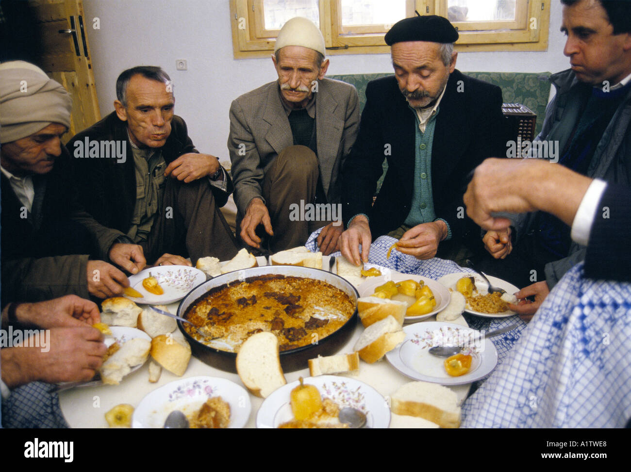 MEN FROM A POOR ALBANIAN FAMILY SHARING A MEAL SITTING ON THE FLOOR ...