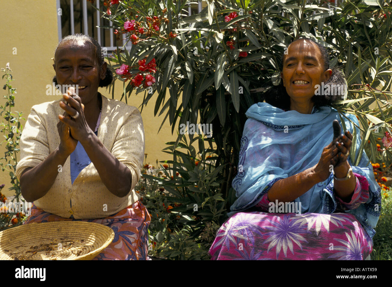 TWO WOMEN WEARING BRIGHTLY COLOURED CLOTHING SINGING AND CLAPPING ...