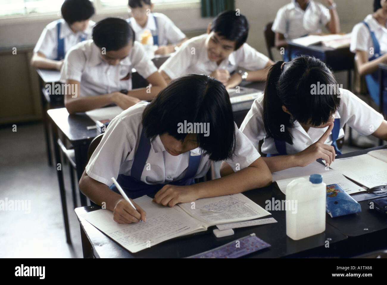 SINGAPORE SCHOOL CLASSROOM PUPILS WRITING IN THEIR EXERCISE BOOKS Stock ...