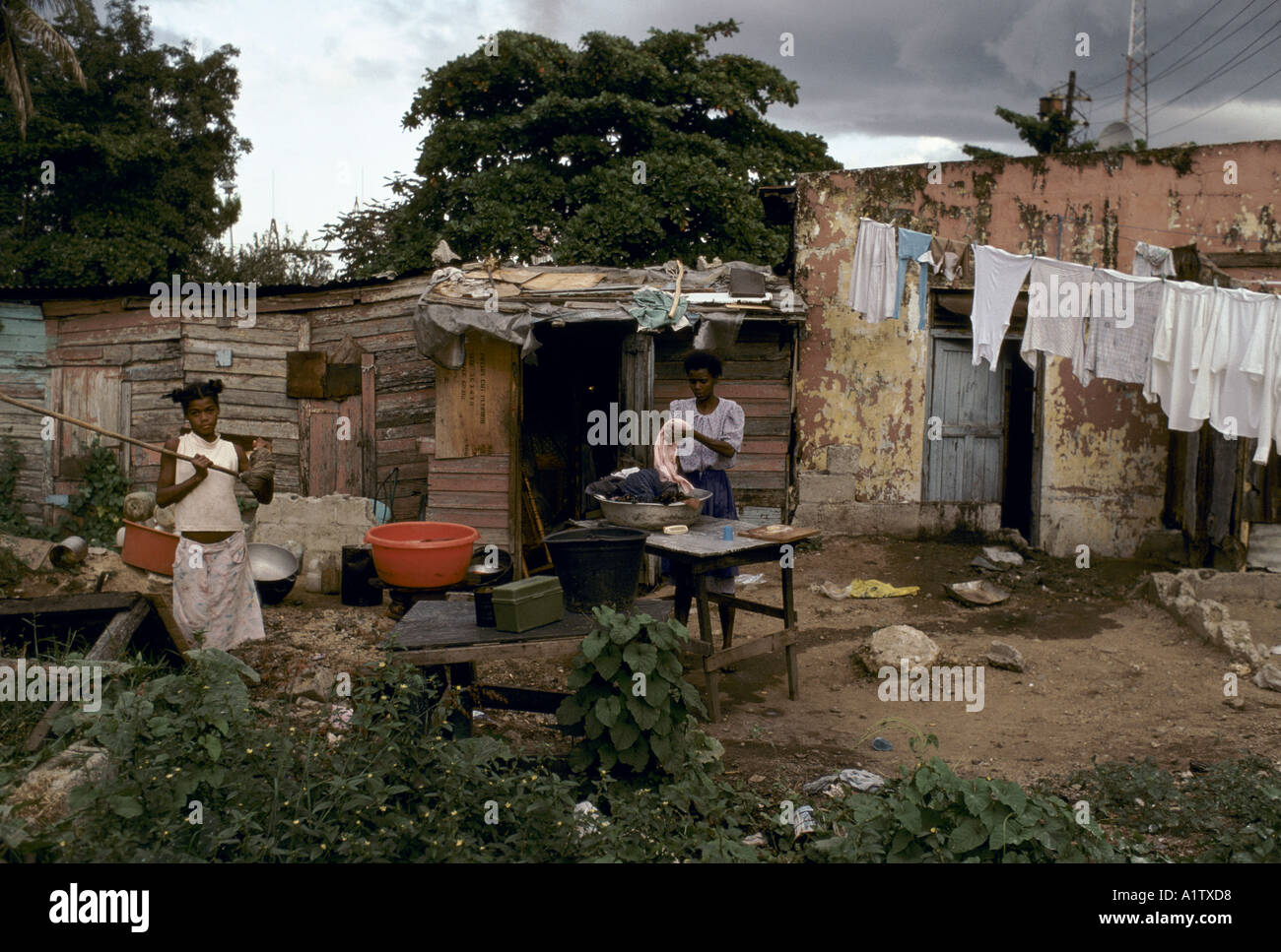 HOUSING IN SANTO DOMINGO. Woman washing clothes in front of small shack ...