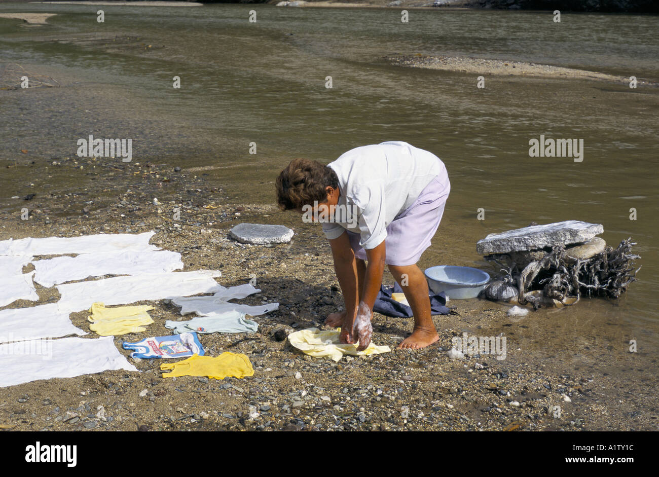 WOMAN WASHING CLOTHES IN THE RIVER AND LAYING THEM OUT TO DRY IN THE ...