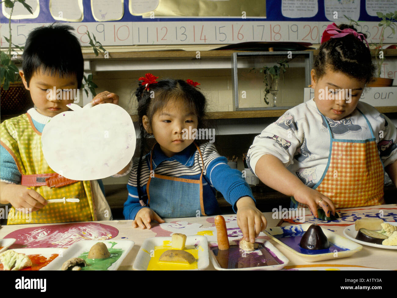 PRIMARY SCHOOL ART LESSON. Three young children use vegetables and ...